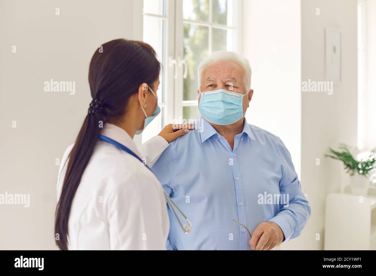 Senior patient and young female doctor, wearing medical face masks ...