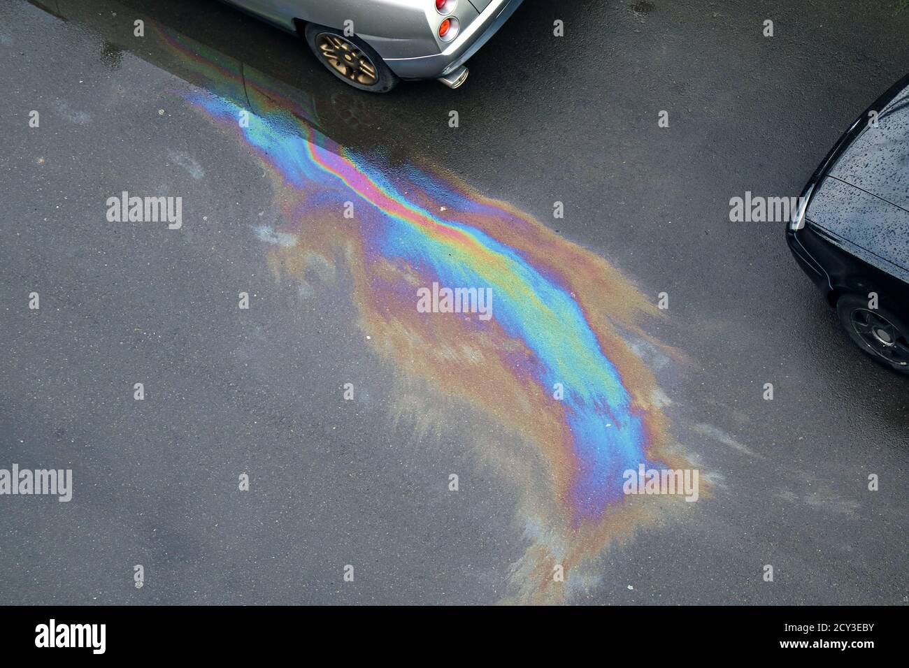 Multi-color patterns on the road from car's lubricating oil after the ...