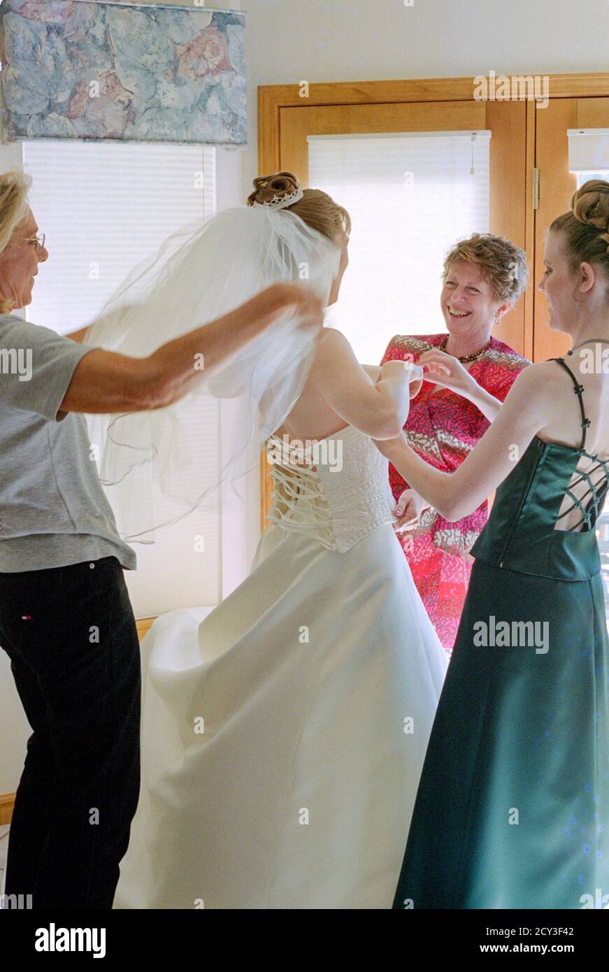 Mother and Bridal Attendants Assist Young Bride with her Wedding Gown ...