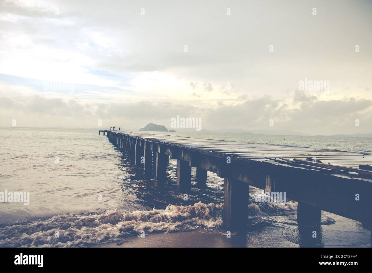 3 people standing at the end of a pier watching the ocean Stock Photo ...