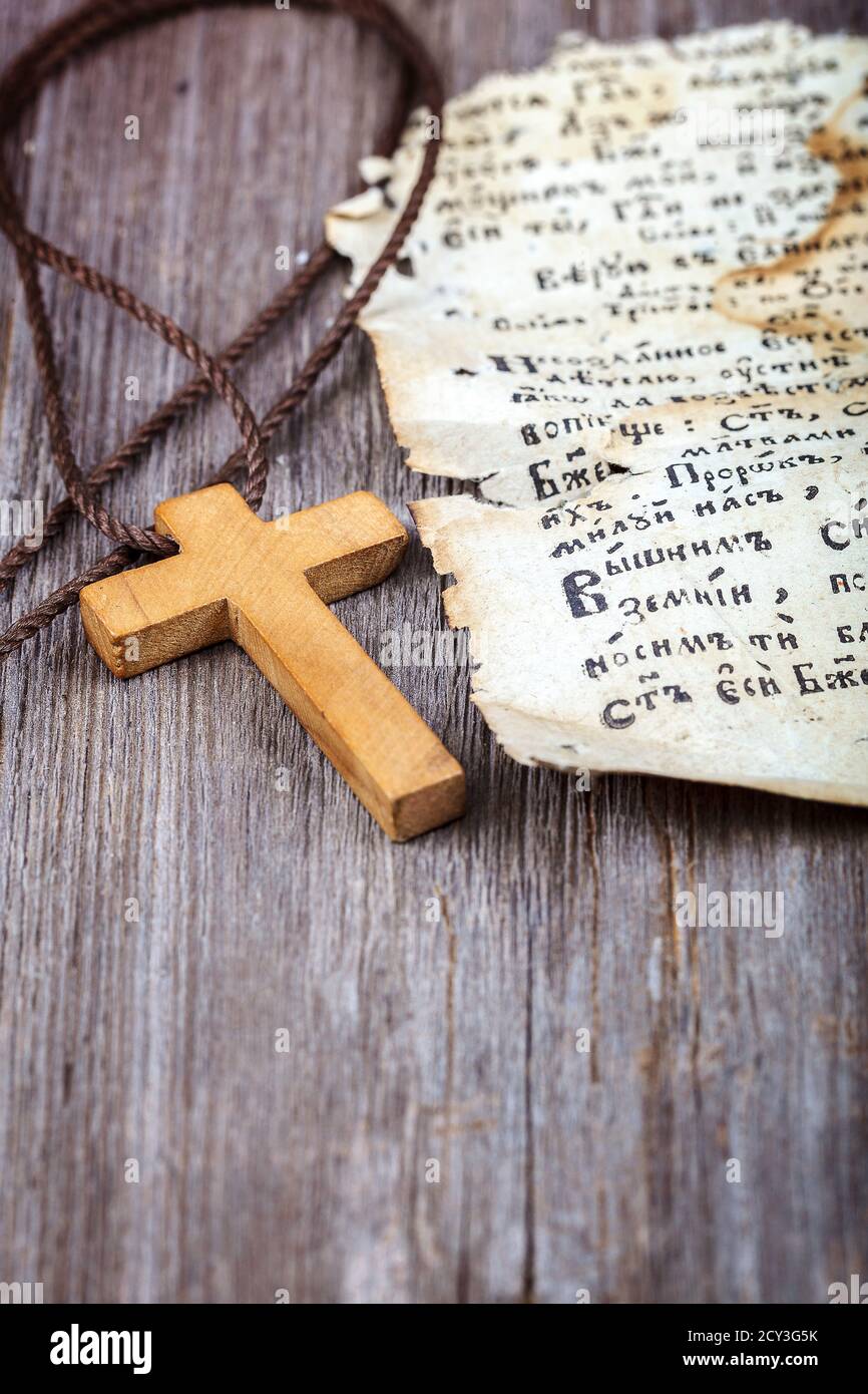A piece of the page of an ancient holy book is a wooden cross Stock ...