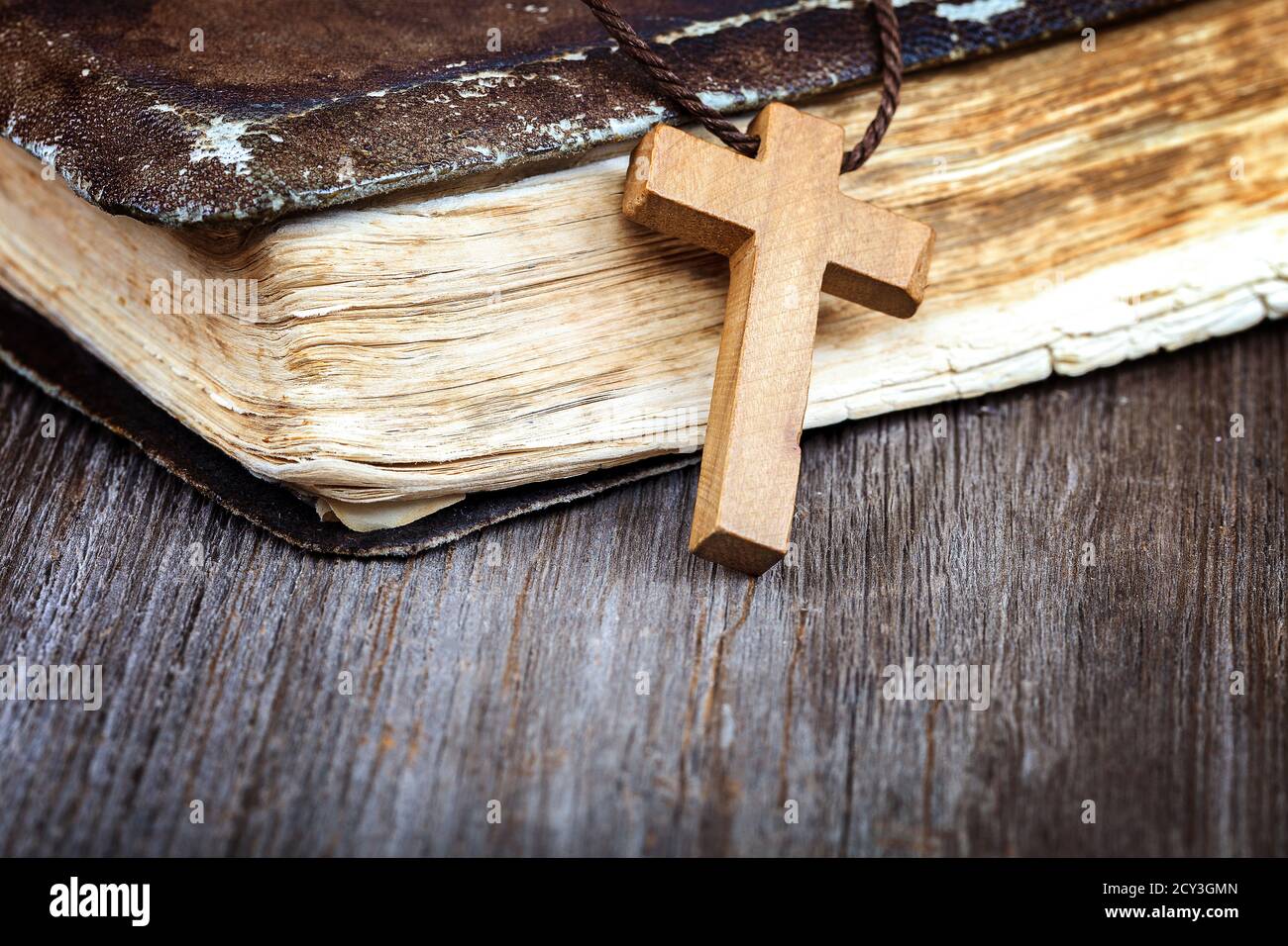 Ancient holy book of a wooden cross on a cord on a wooden background ...