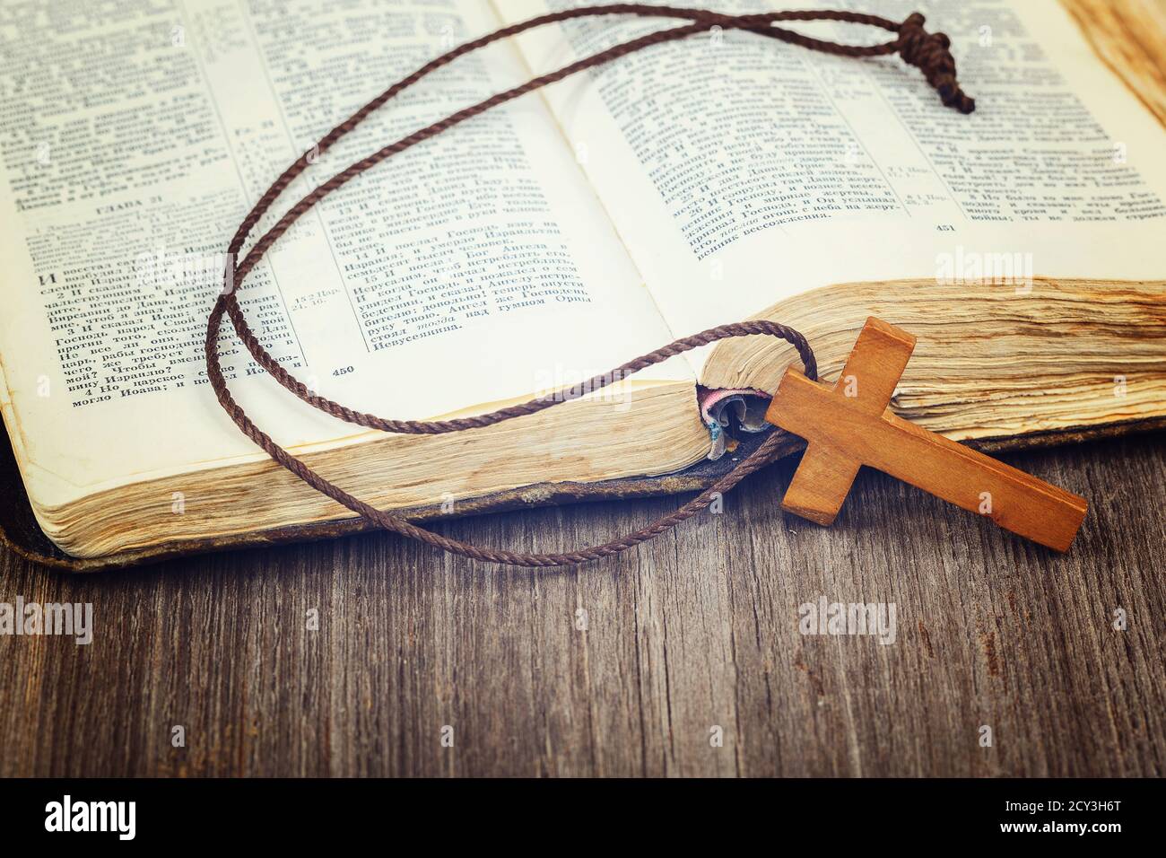 Ancient holy book of a wooden cross on a cord on a wooden background ...