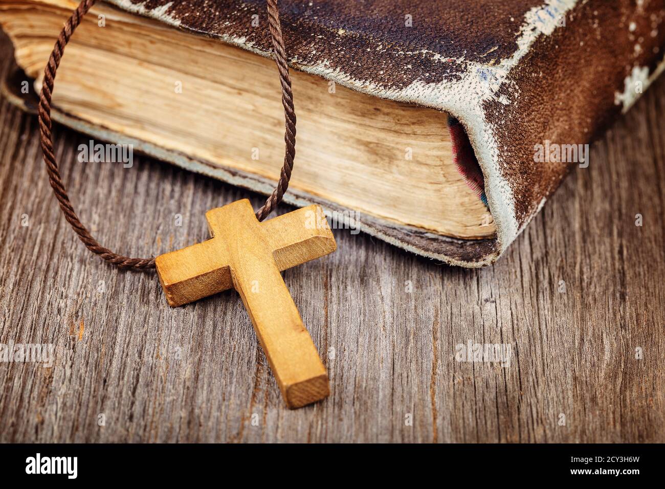 Ancient holy book of a wooden cross on a cord on a wooden background ...