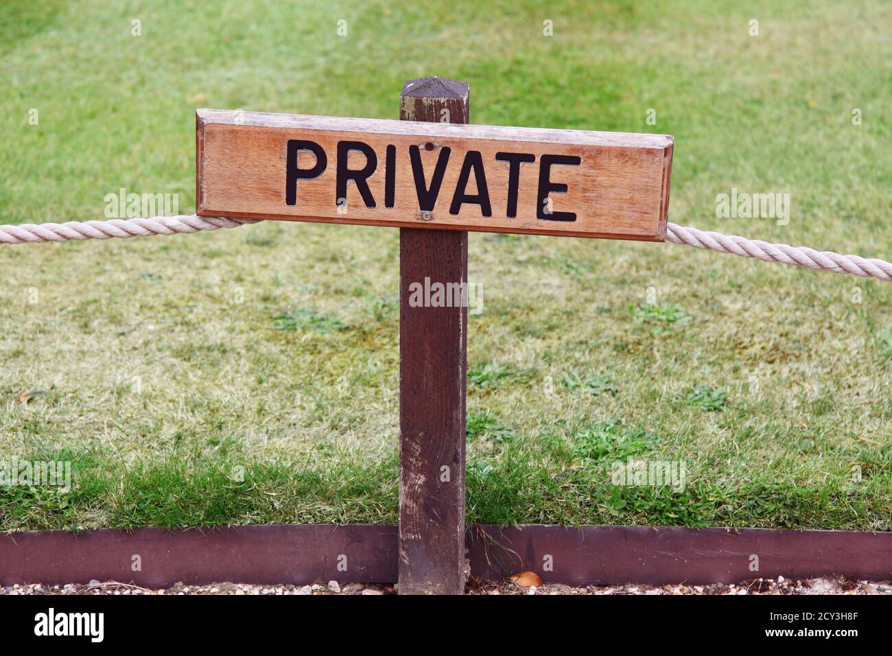 Private sign and rope marking an area of green grass lawn as off limits ...