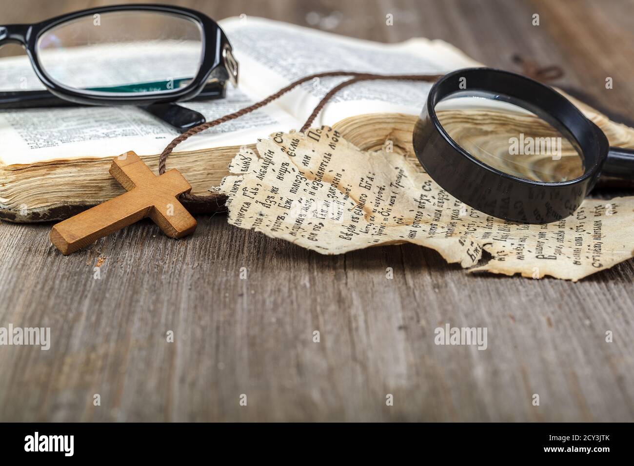 Ancient holy book of a wooden cross on a cord on a wooden background ...