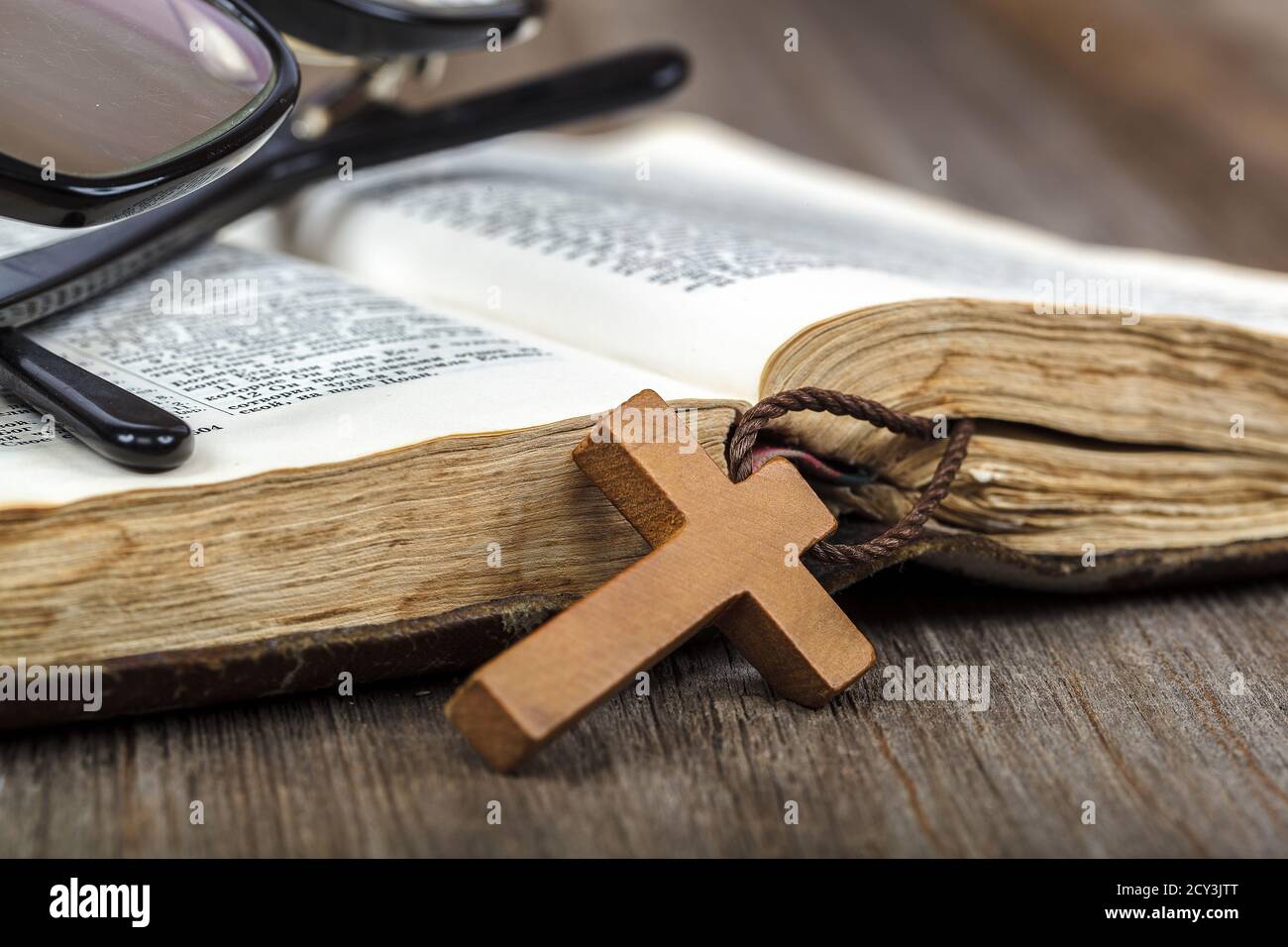 Ancient holy book of a wooden cross on a cord on a wooden background ...