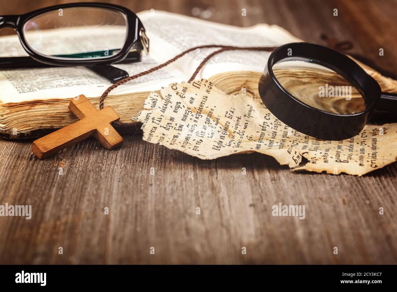 Ancient holy book of a wooden cross on a cord on a wooden background ...