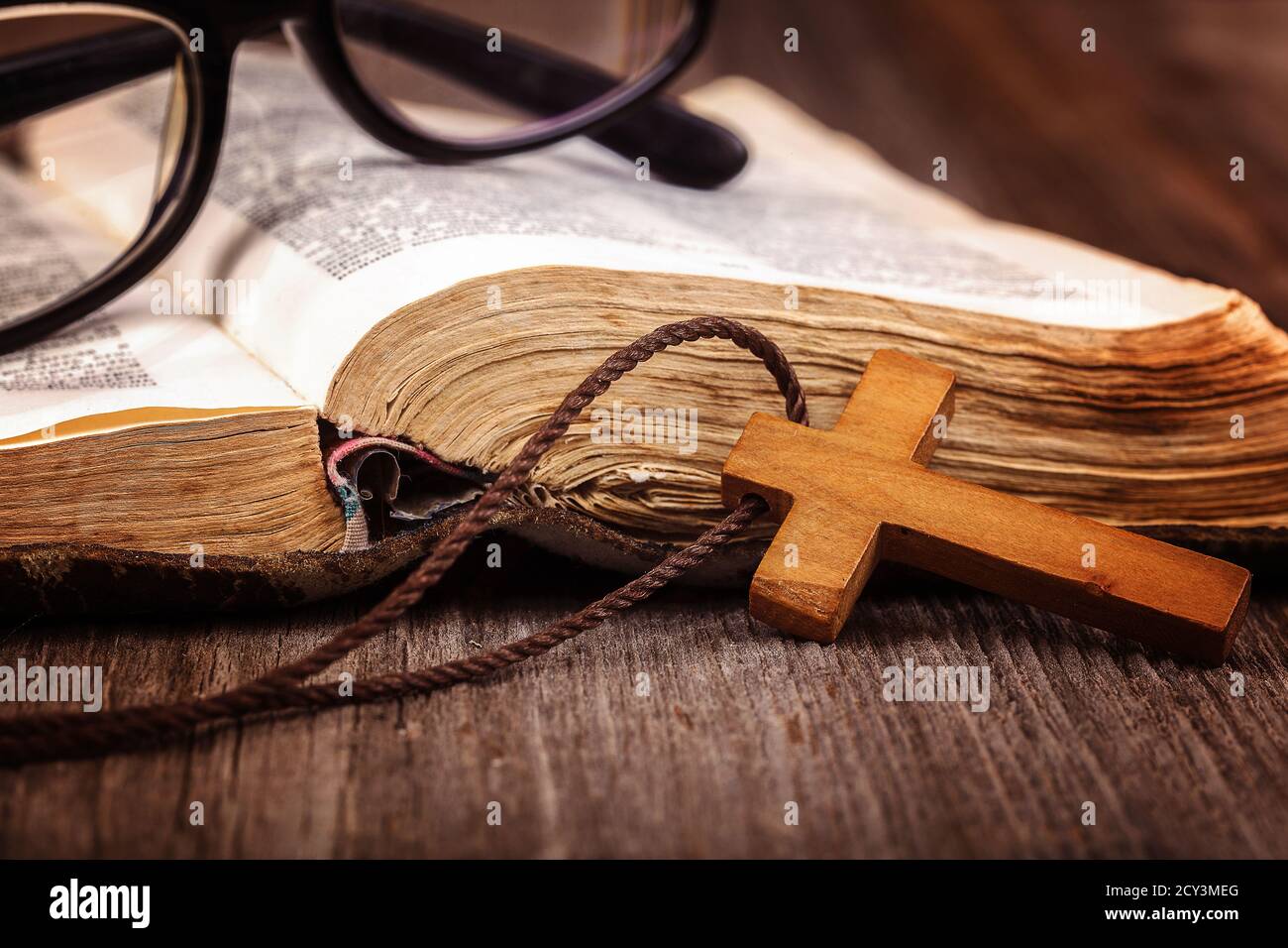 Ancient holy book of a wooden cross on a cord on a wooden background ...