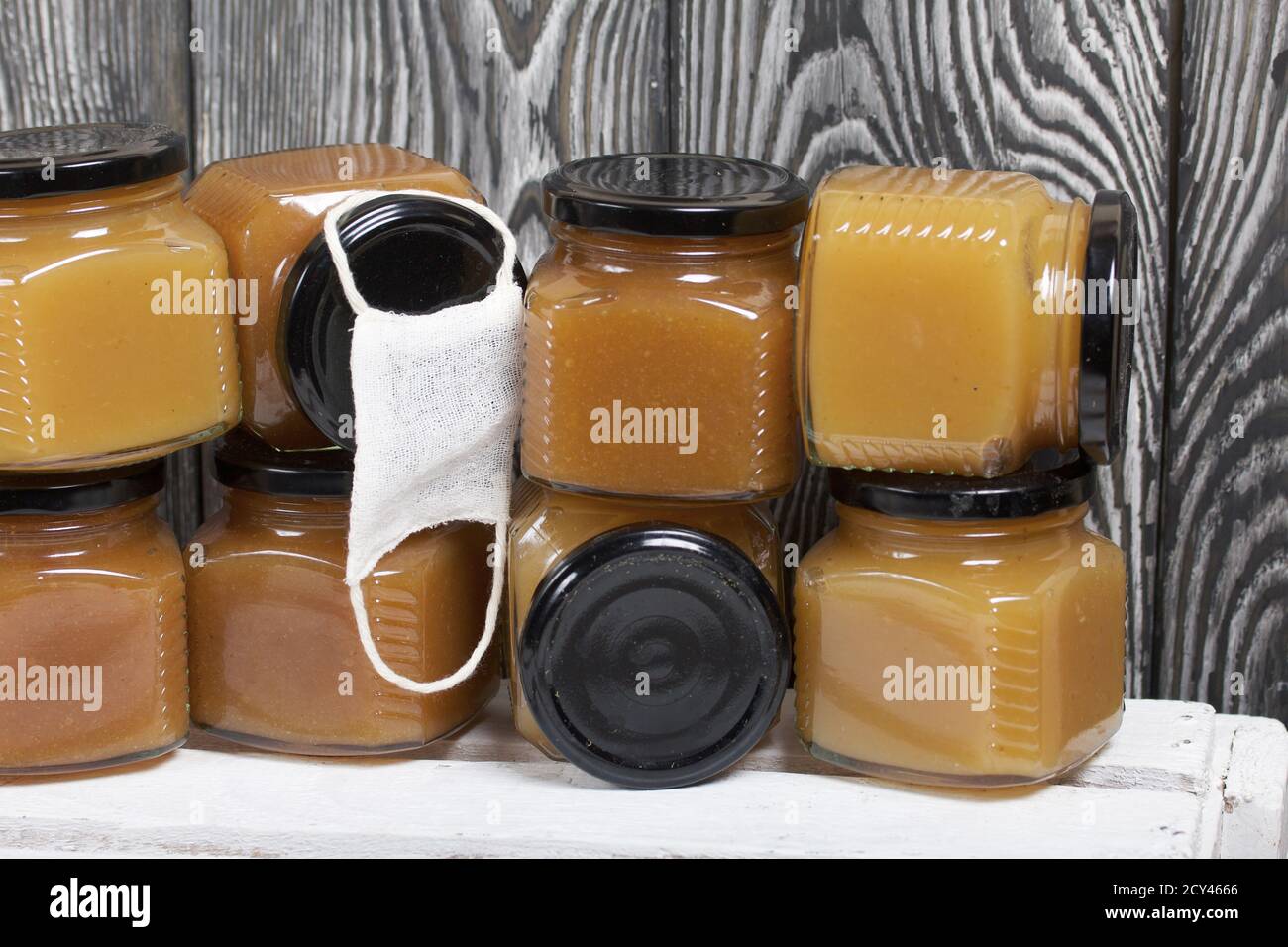 Fruit jam in jars. He is wearing a medical mask. Stands on a white ...