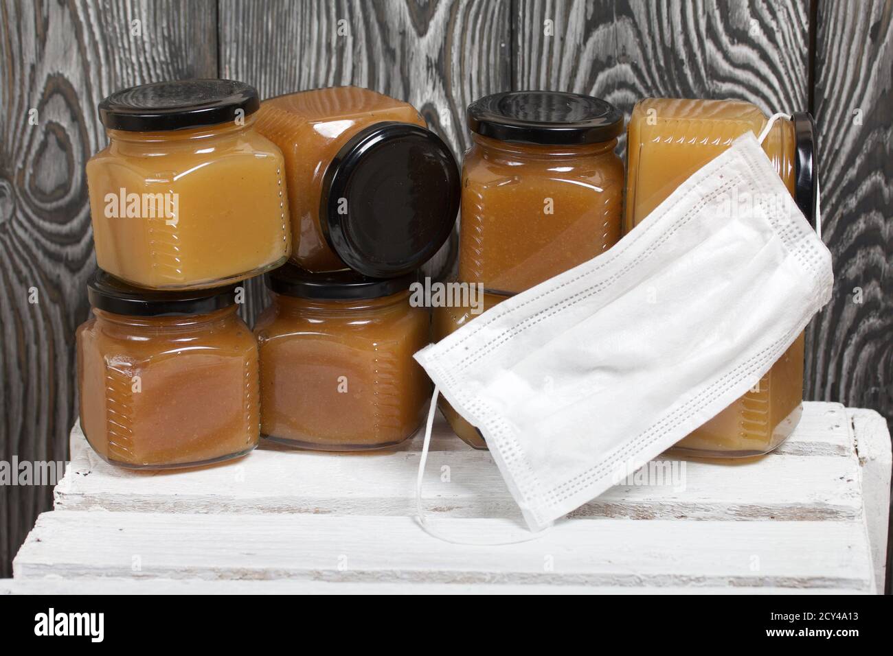 Fruit jam in jars. He is wearing a medical mask. Stands on a white ...