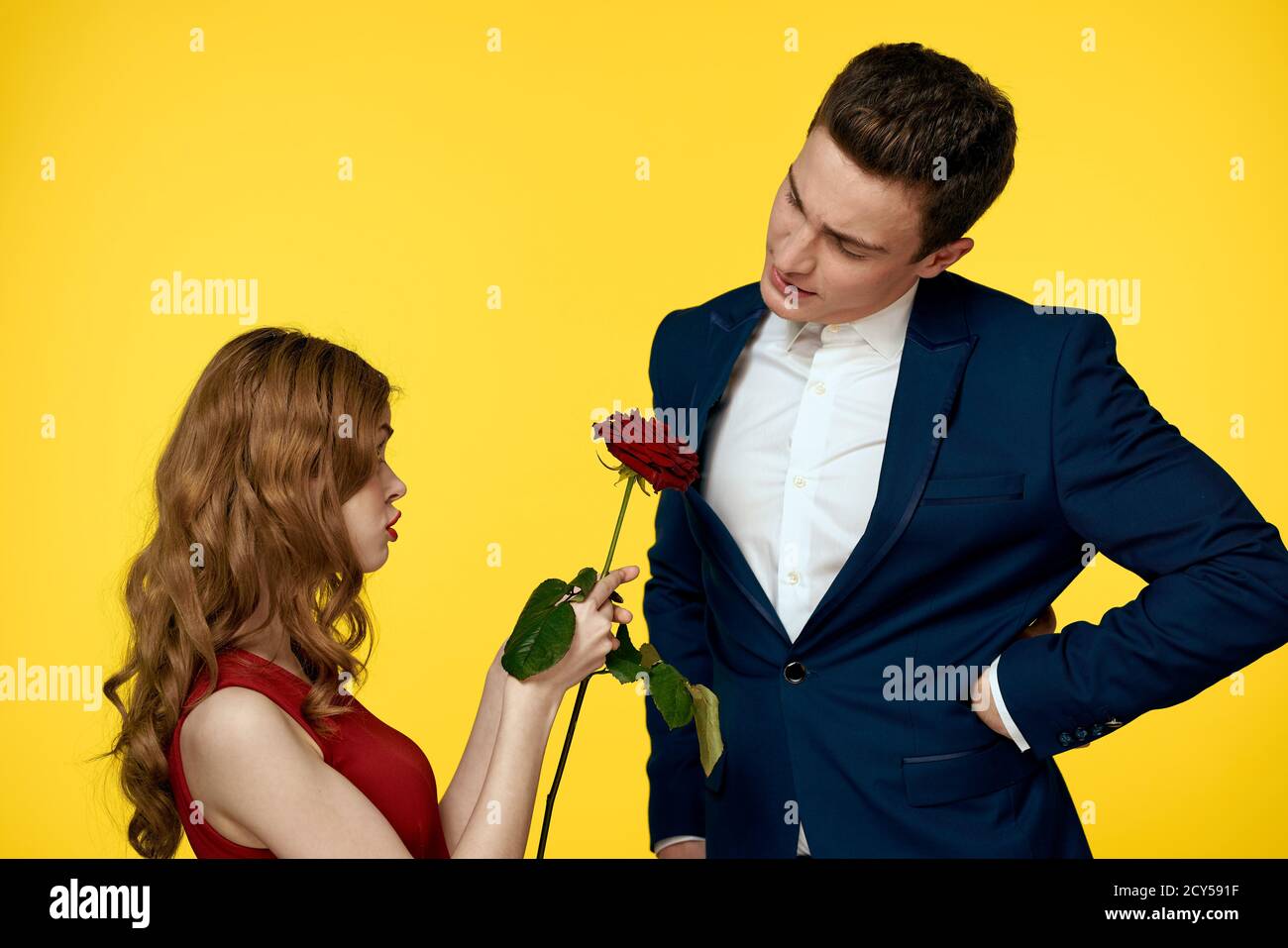 A romantic man hugs a woman in a red dress with a rose in his hand on a ...