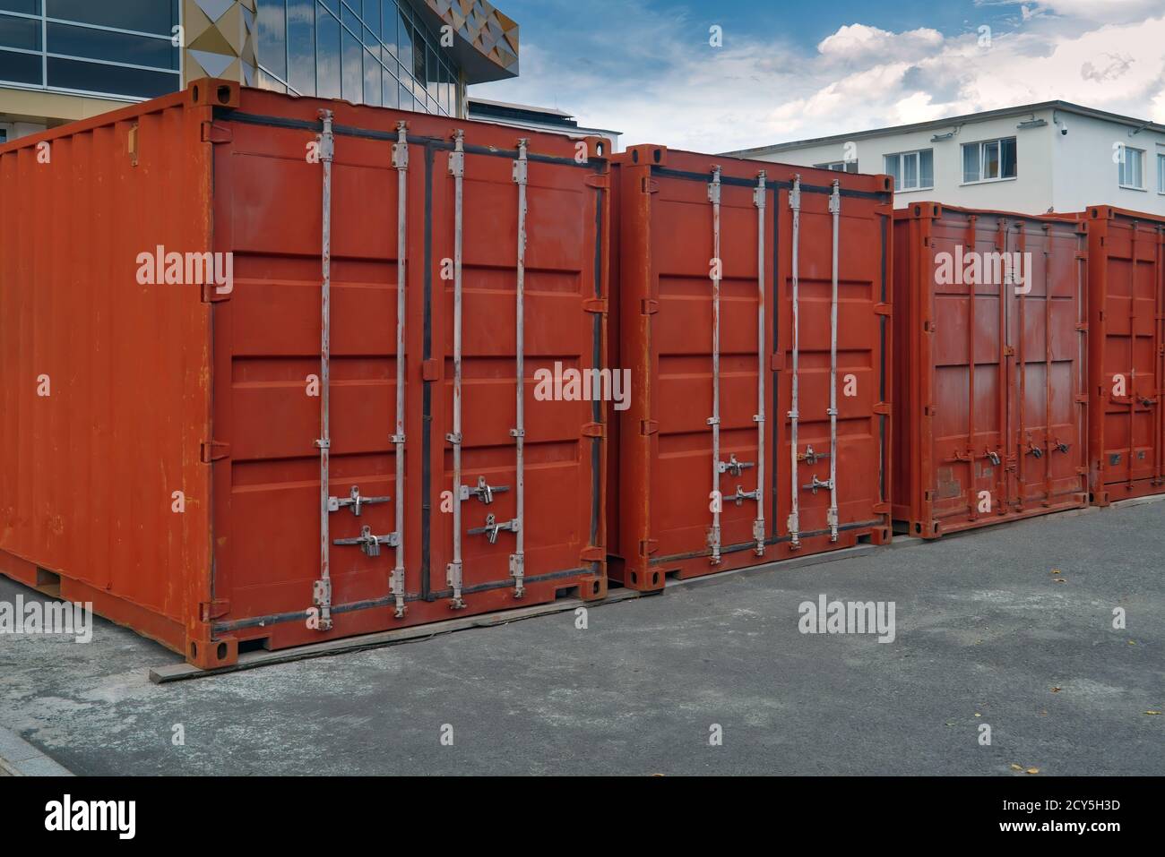 Orange metal shipping containers stand against a building wall Stock ...