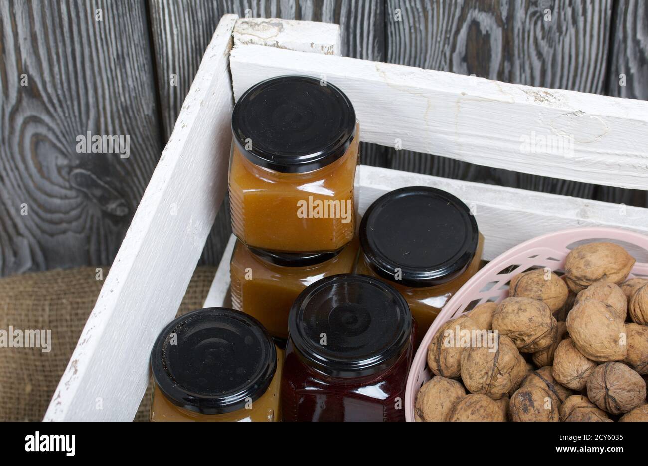 A basket with walnuts. Jars of jam. Stand in a white wooden box Stock ...