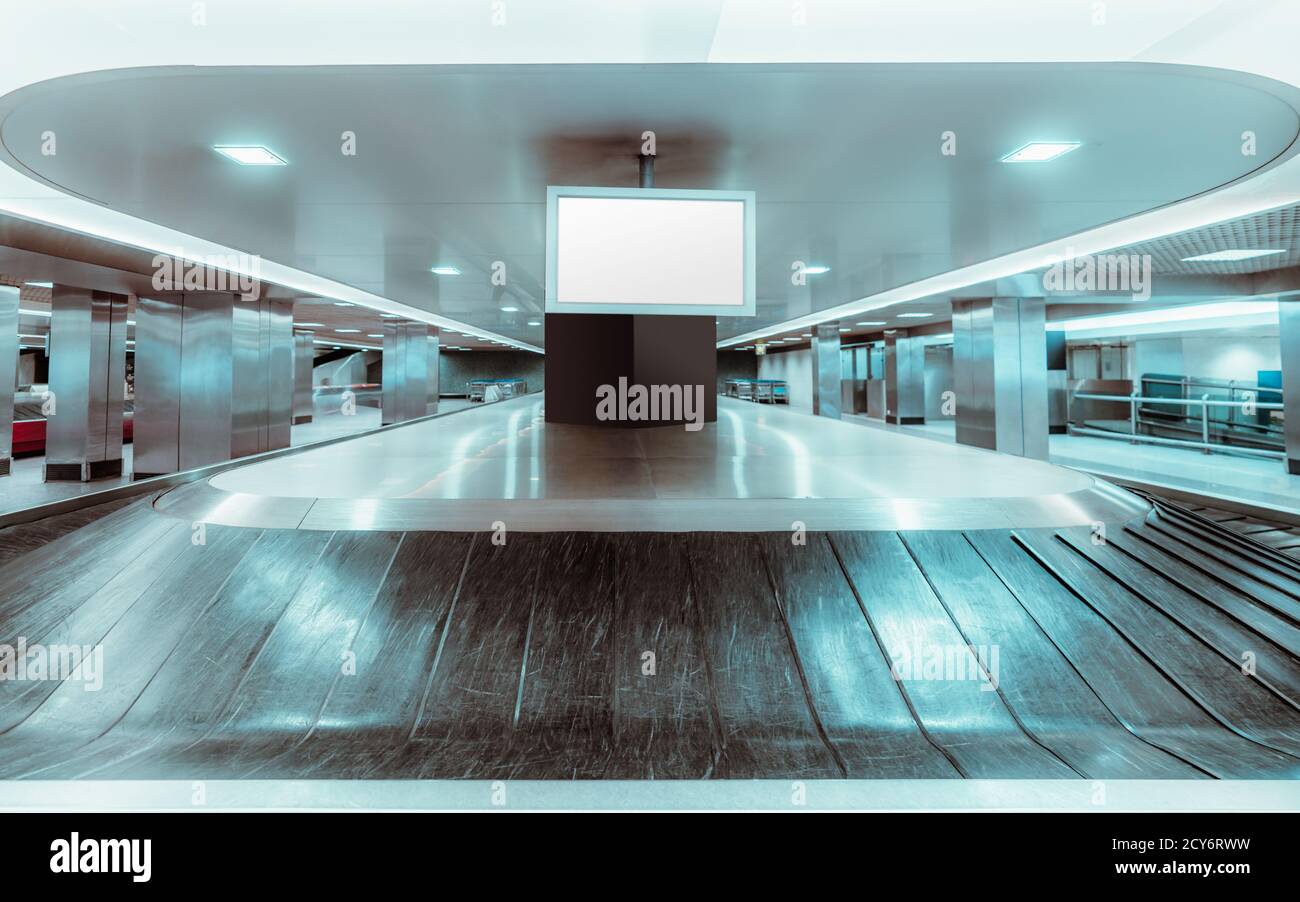A frontal wide-angle view of a baggage claim area in a hall of an ...