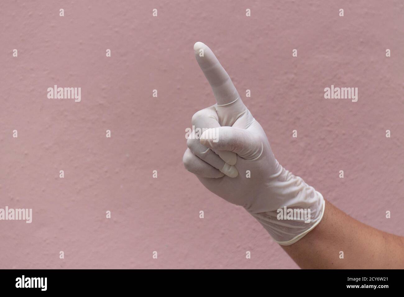 Hand of a person in a white plastic glove pointing with the forefinger ...