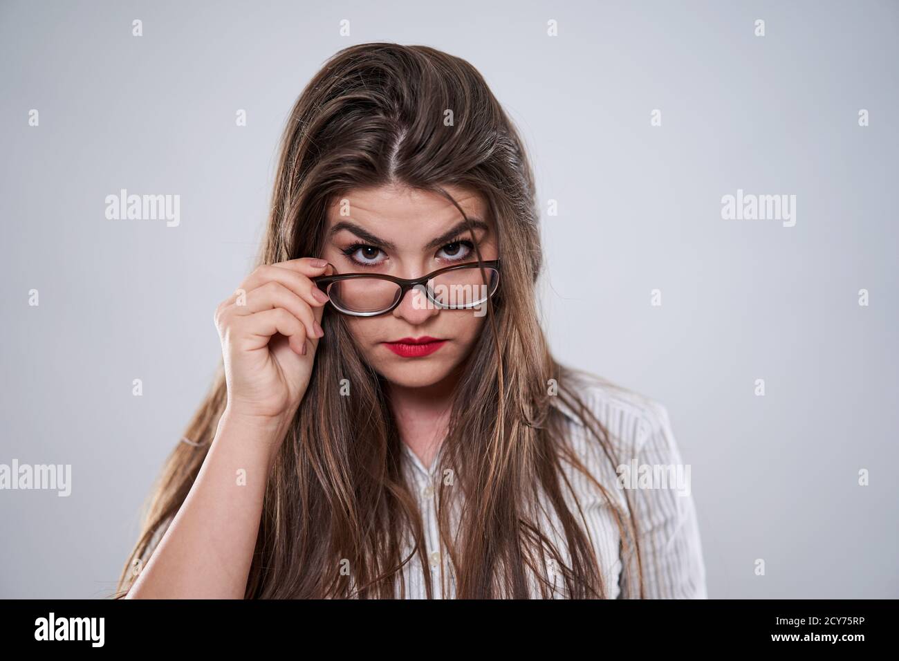 Closeup of a doubtful suspicious young businesswoman in glasses over ...