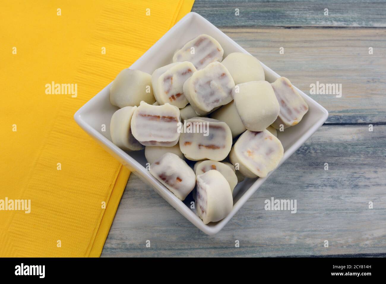 Caramel layered snack dipped in white chocolate in white snack bowl ...