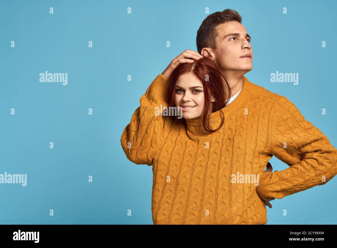 couple in love in yellow sweater posing against blue background cropped ...