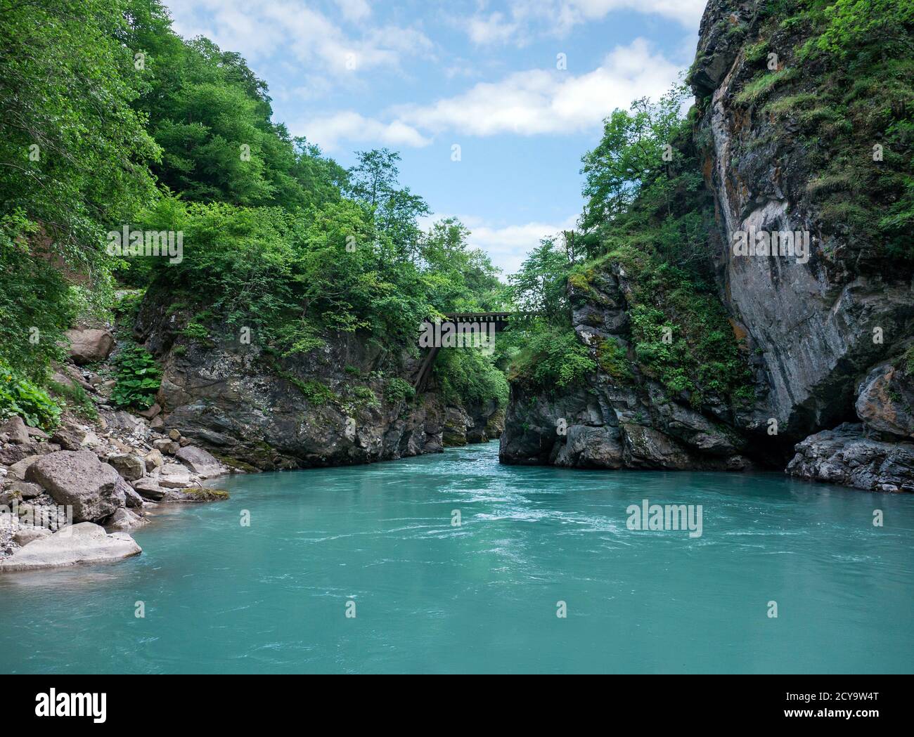 Azure backwater of mountain river. View of the bridge on the wild water ...