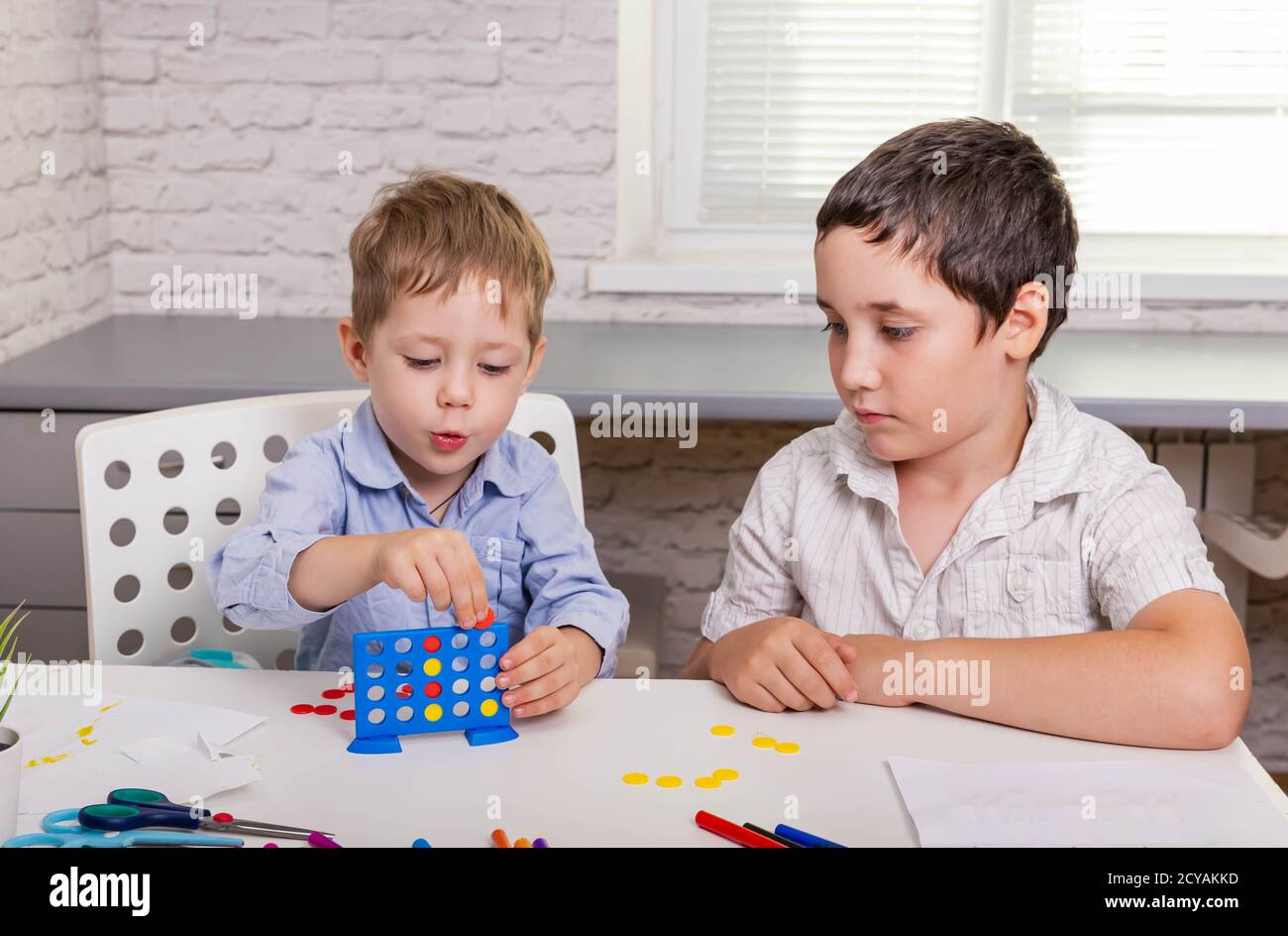 Two children are playing together board game on the table at home Stock ...