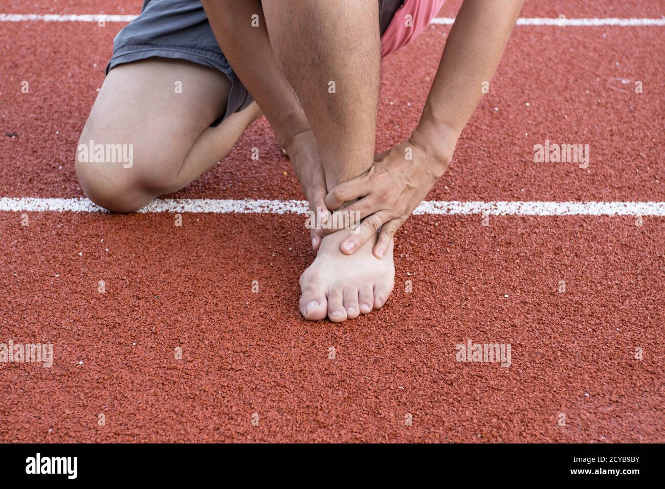 man ankle injury after running at Running field Stock Photo - Alamy