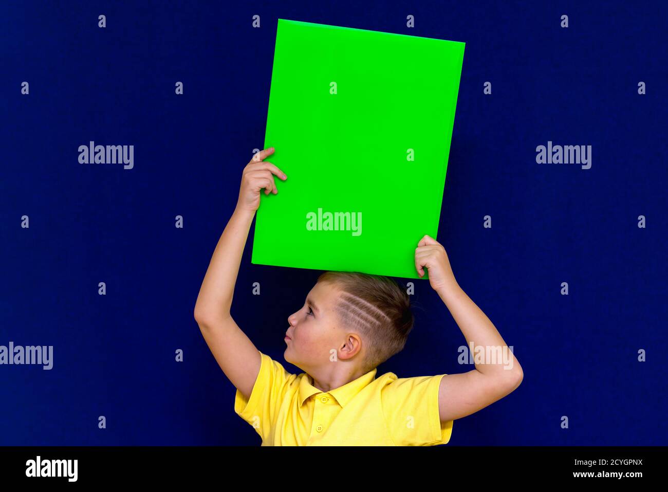 Side view Happy nice calm caucasian child boy holding a poster overhead ...