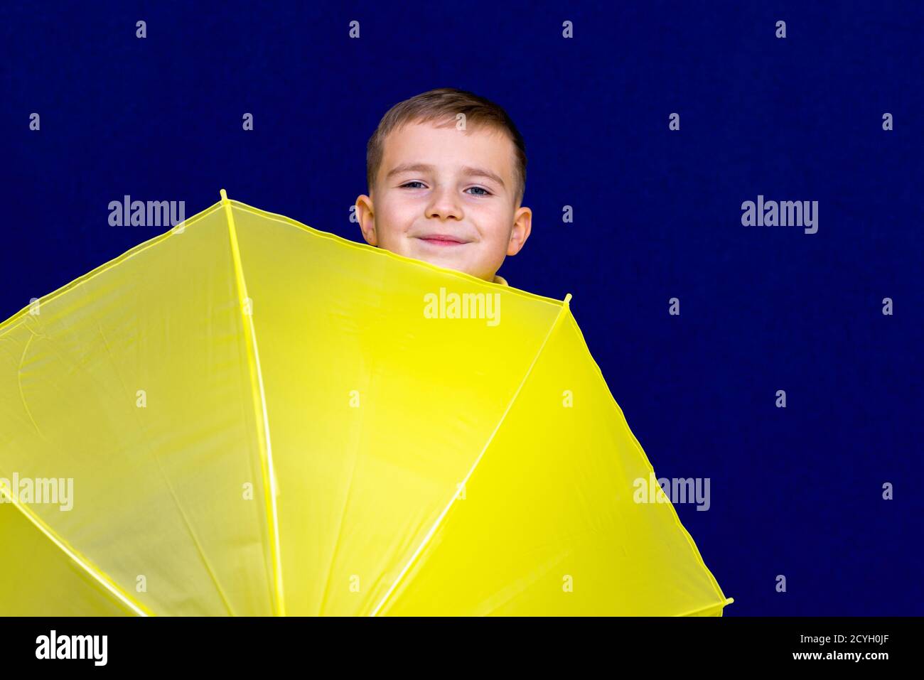 Attractive surprised caucasian blond schoolboy scatter umbrellas hiding ...