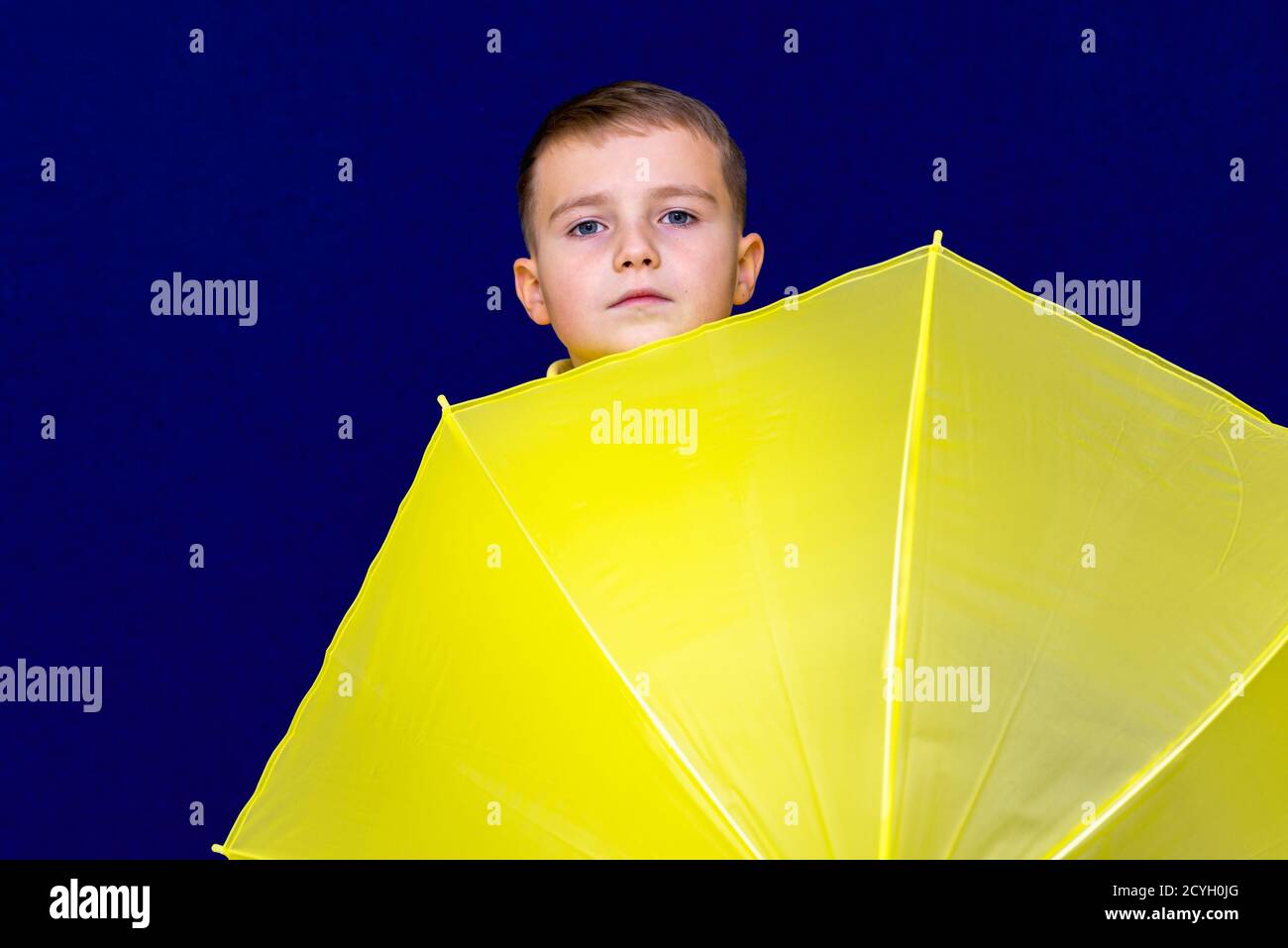 Attractive surprised caucasian blond schoolboy scatter umbrellas hiding ...