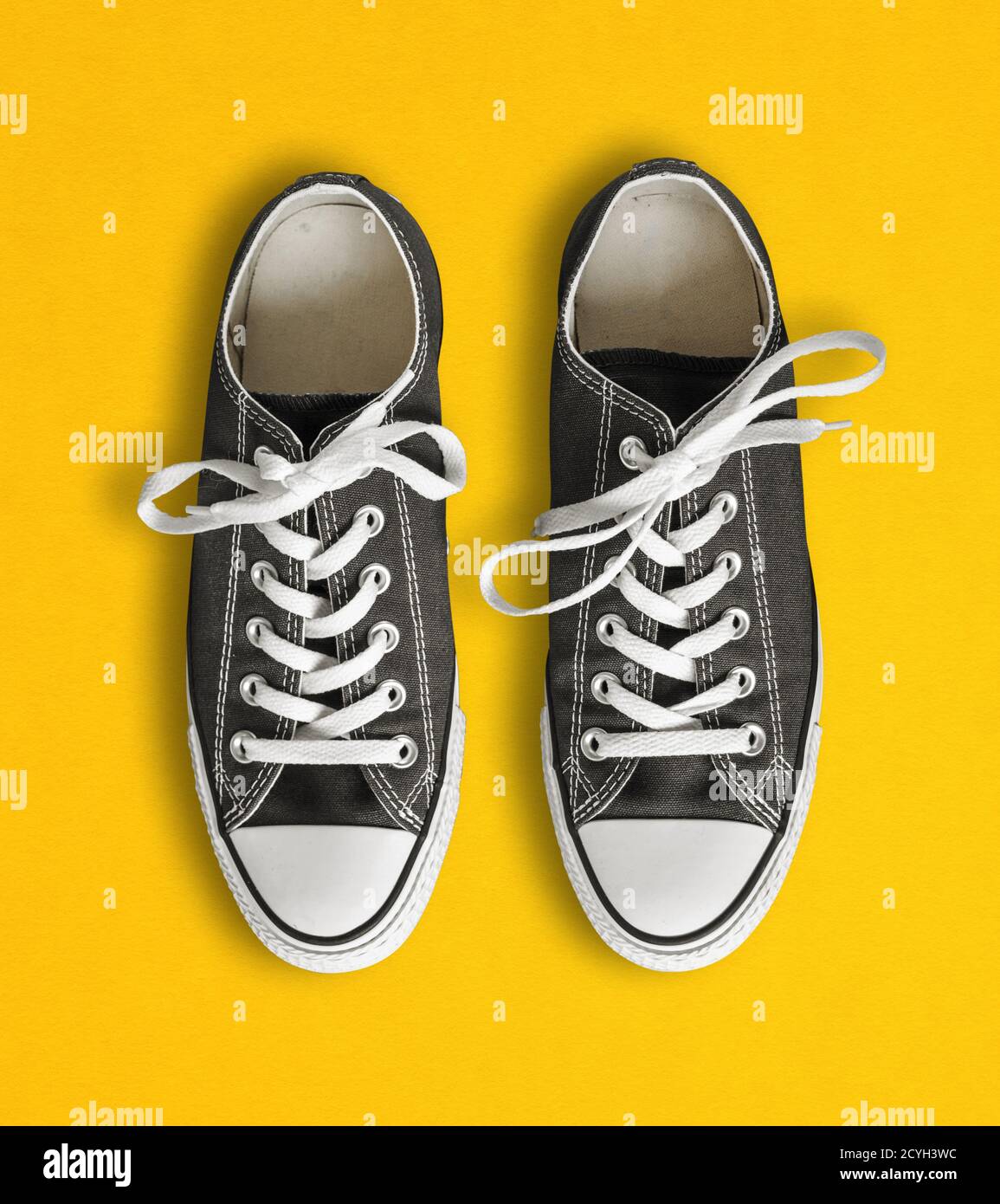 Black generic sneakers isolated on yellow background Stock Photo - Alamy