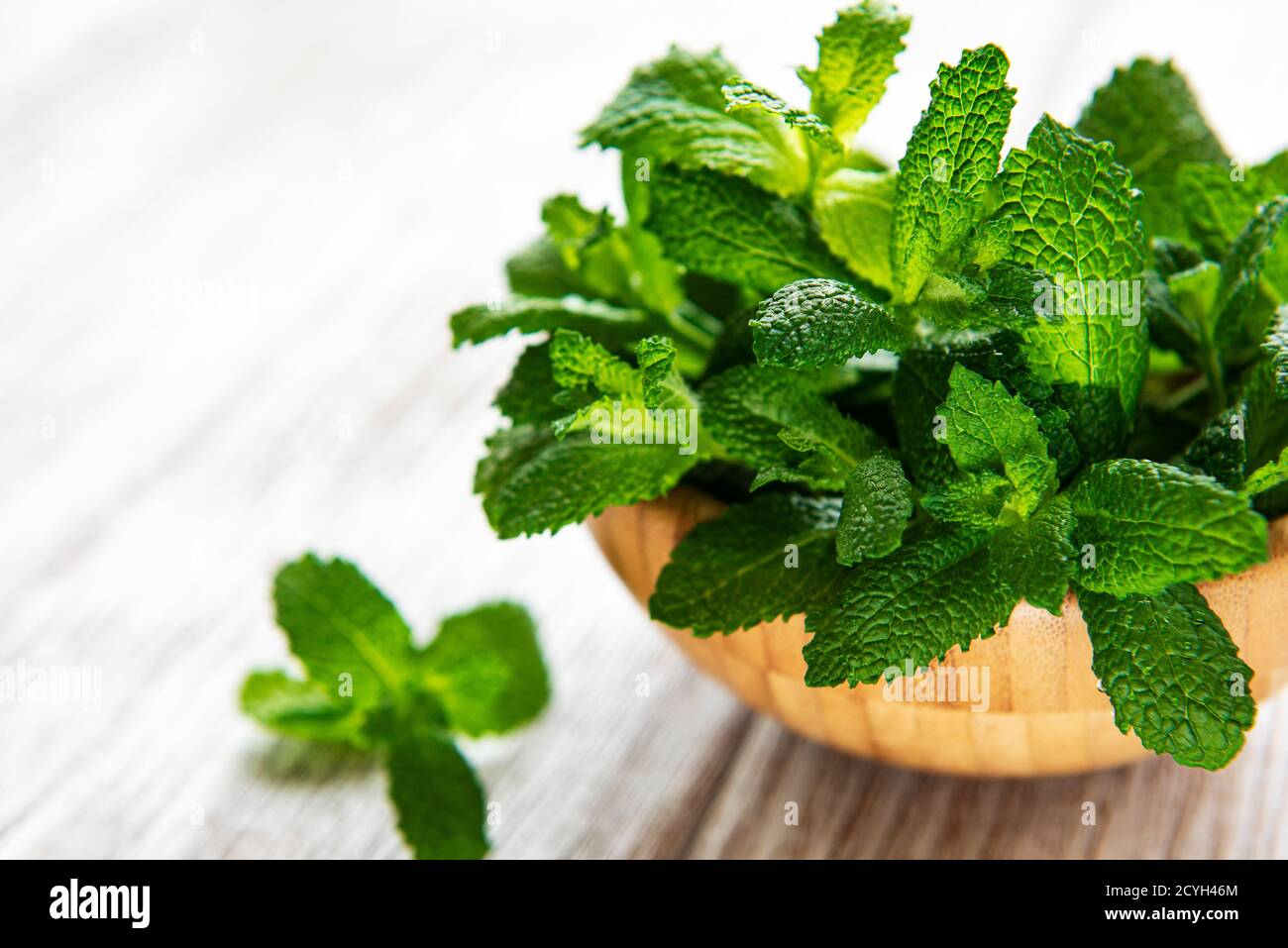Bowl with a bunch of fresh mint on the old wooden table. The concept of ...