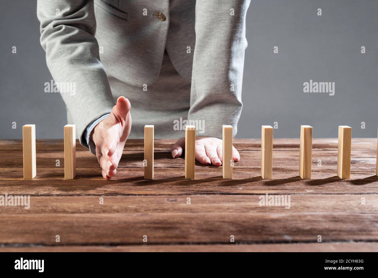 Business woman interrupting domino effect Stock Photo - Alamy