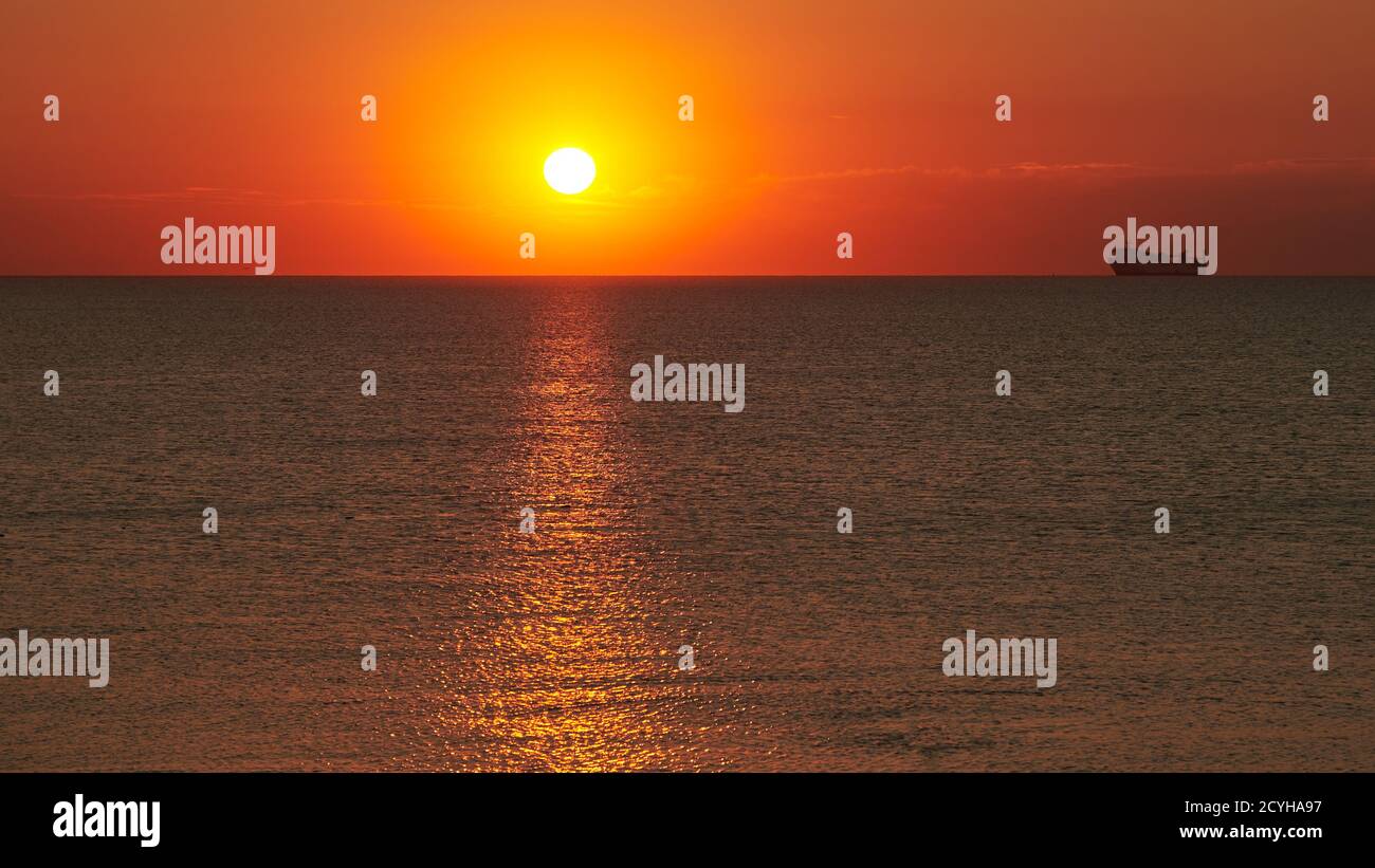 Sunset on a cloudless sky on the sea, ships standing on the horizon ...