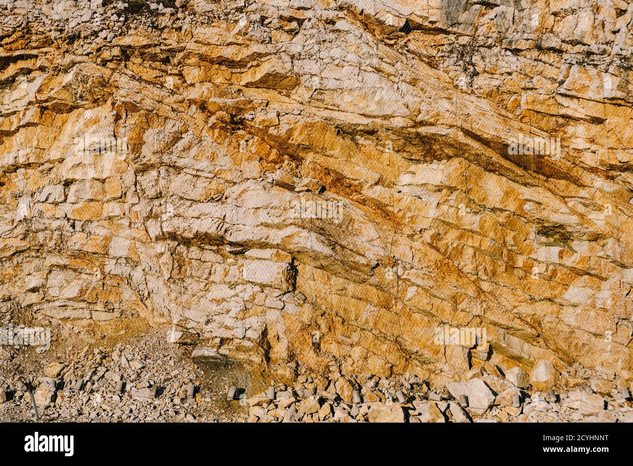 Layered stones near the road are tightened with a metal mesh netting to ...