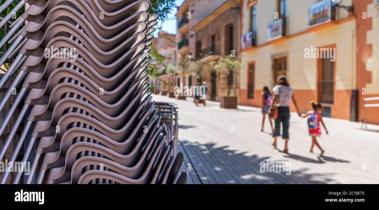 Chairs piled up together and blurred people walking Stock Photo - Alamy