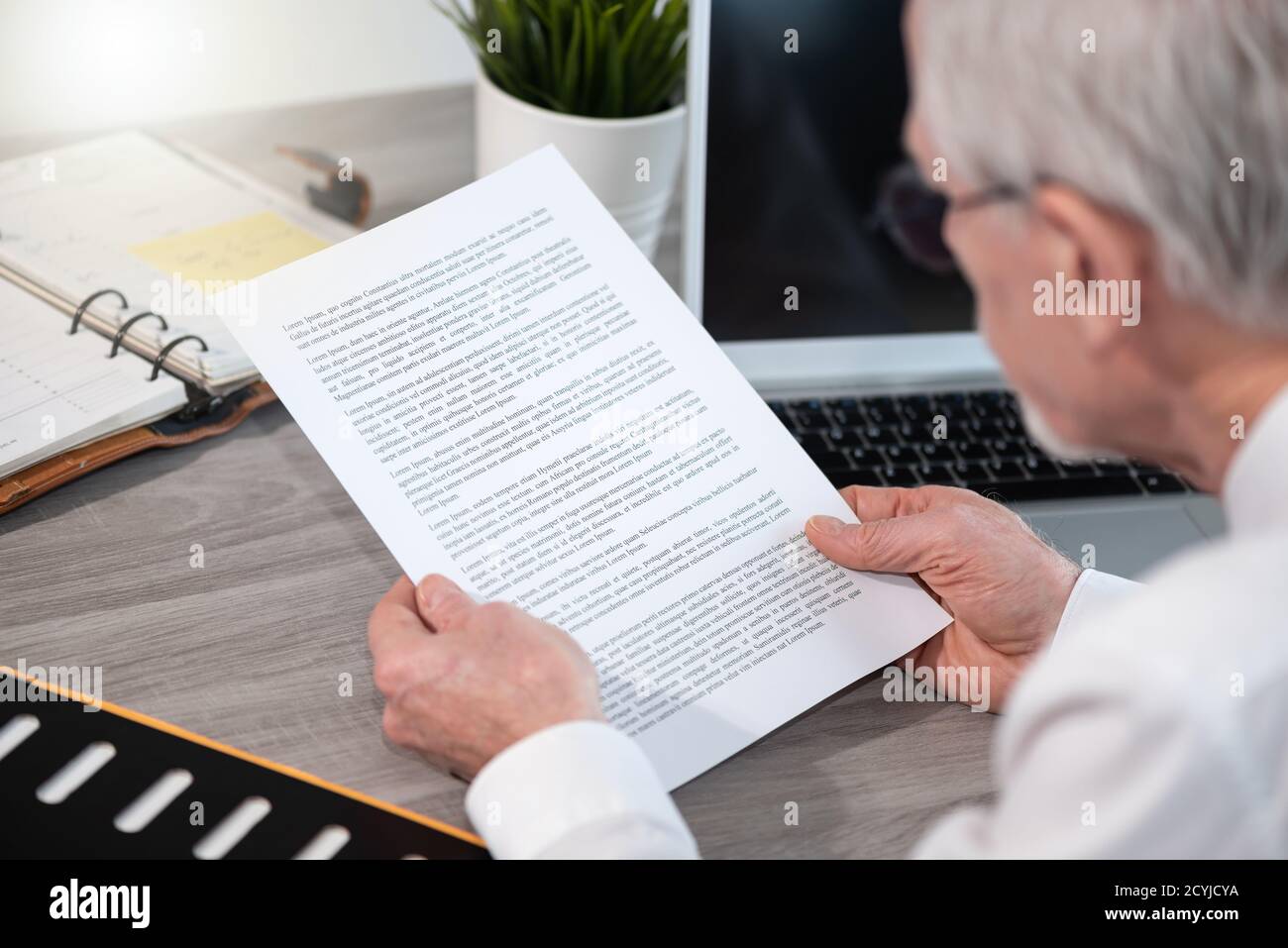 Senior businessman checking document in office Stock Photo - Alamy