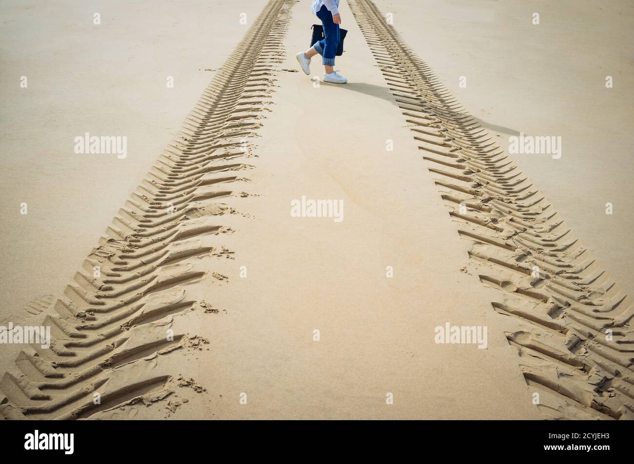Person walking on the sand at the beach through vehicle traces Stock ...
