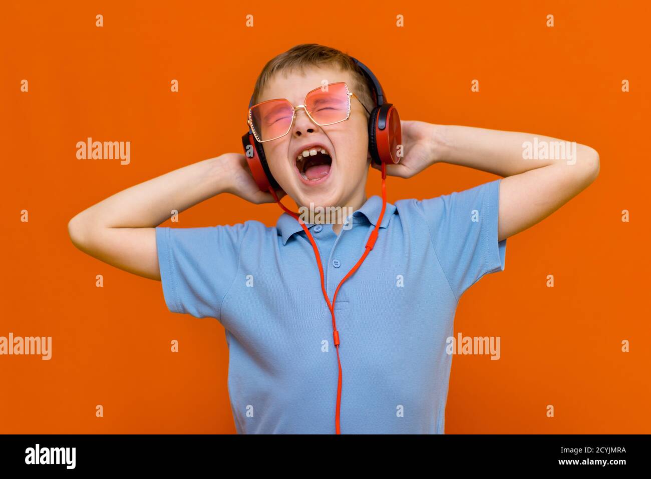 attracive young kid wearing red glasses is listening music with red ...