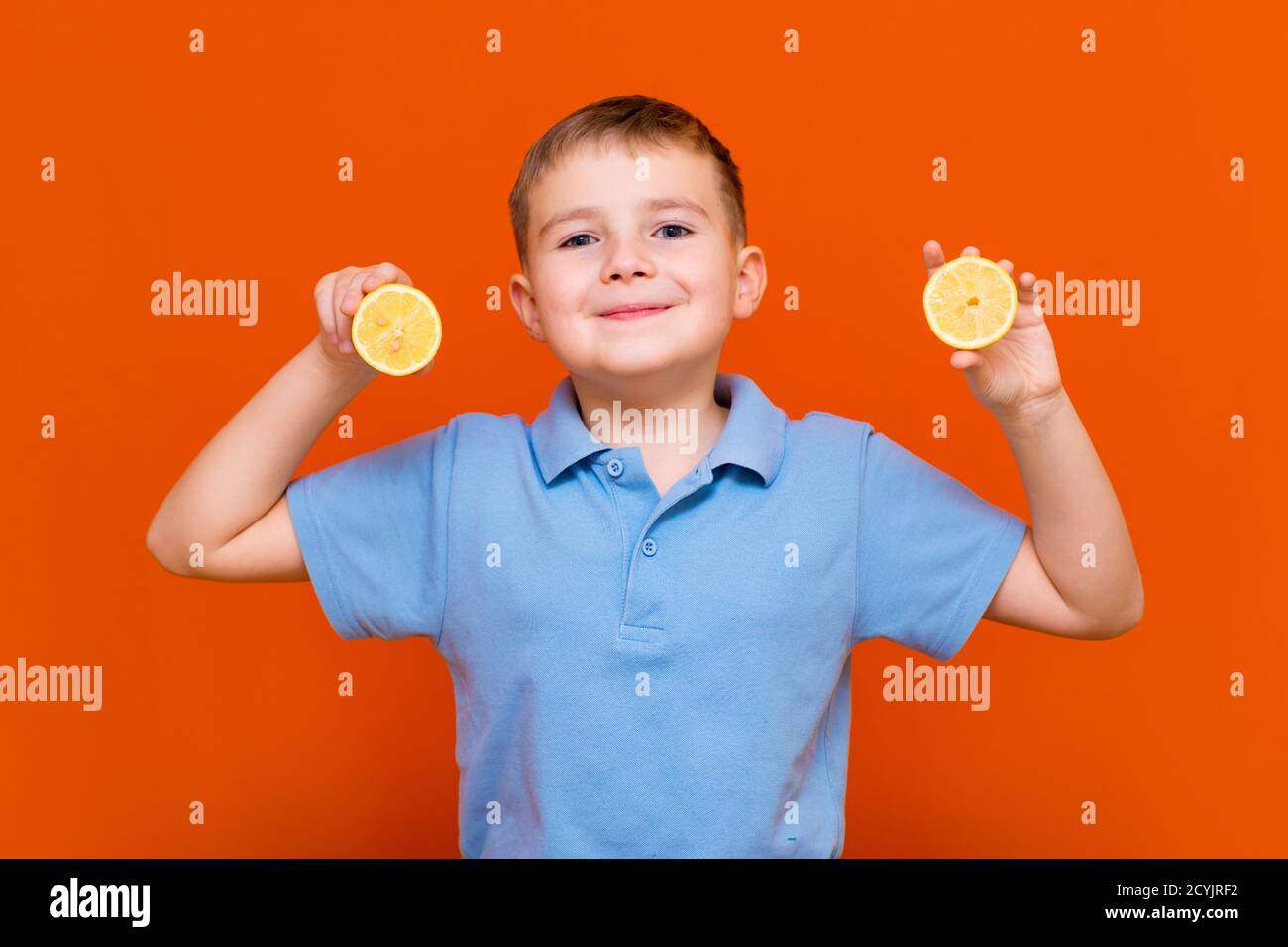 Close up Caucasian young child shows raw slices of lemon on a orange ...