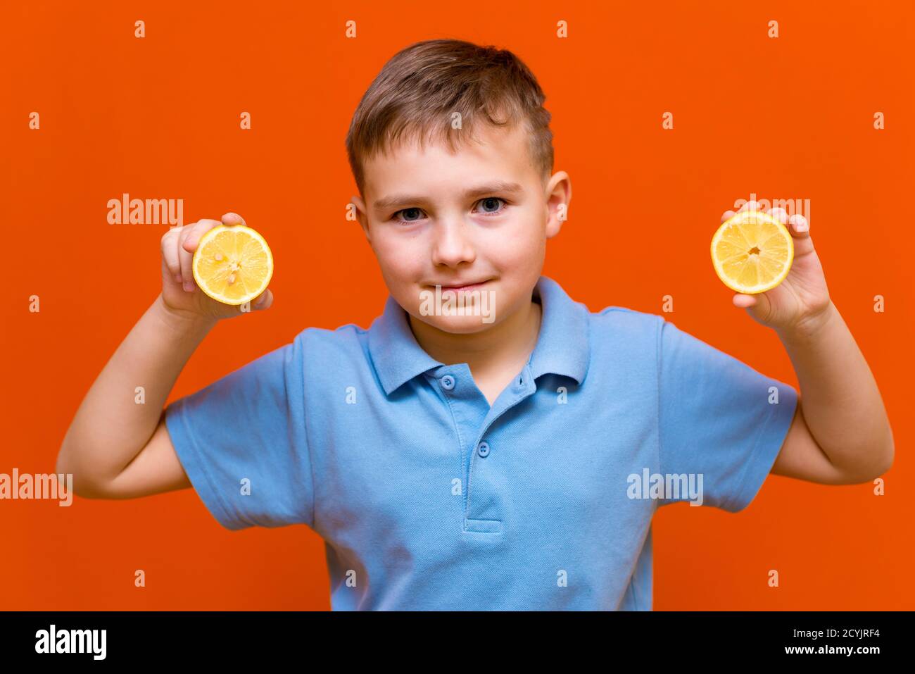 Close up Caucasian young child shows raw slices of lemon on a orange ...