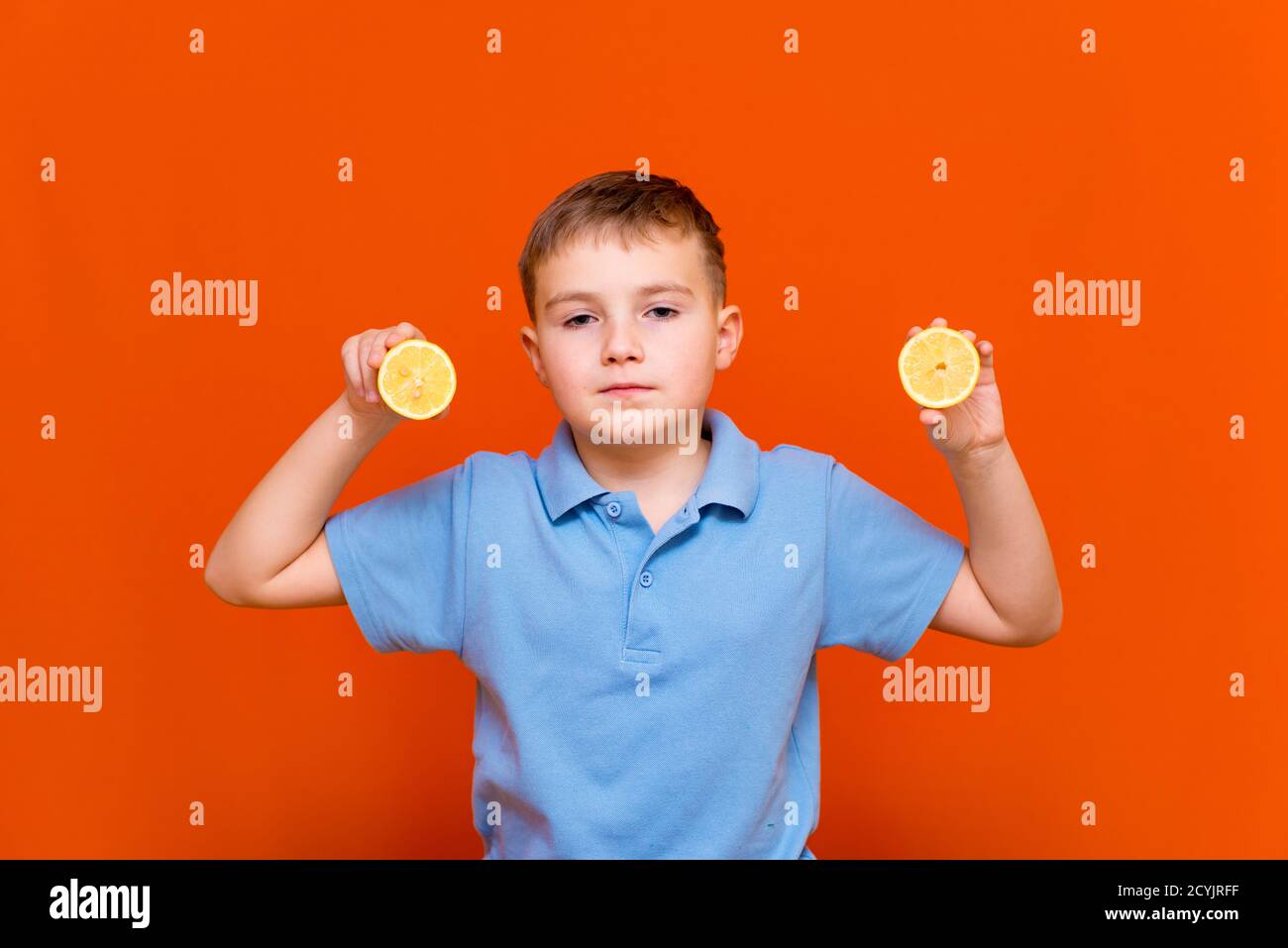 Close up Caucasian young child shows raw slices of lemon on a orange ...