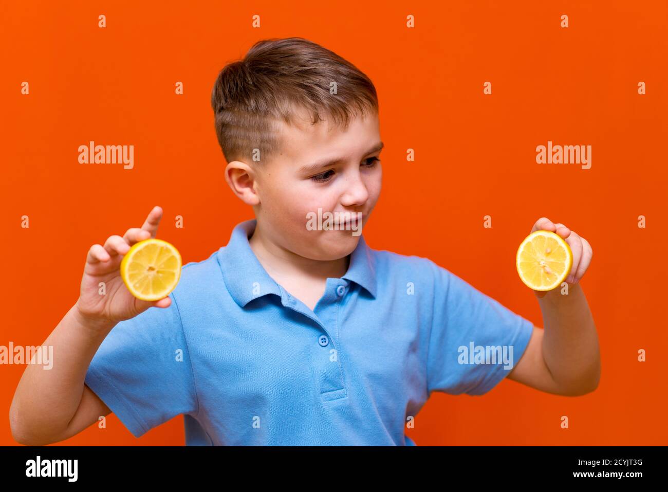 Close up Caucasian young child shows raw slices of lemon on a orange ...