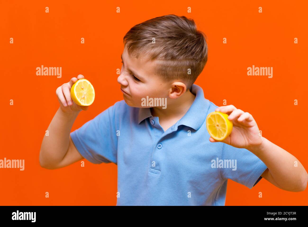 Close up Caucasian young child shows raw slices of lemon on a orange ...