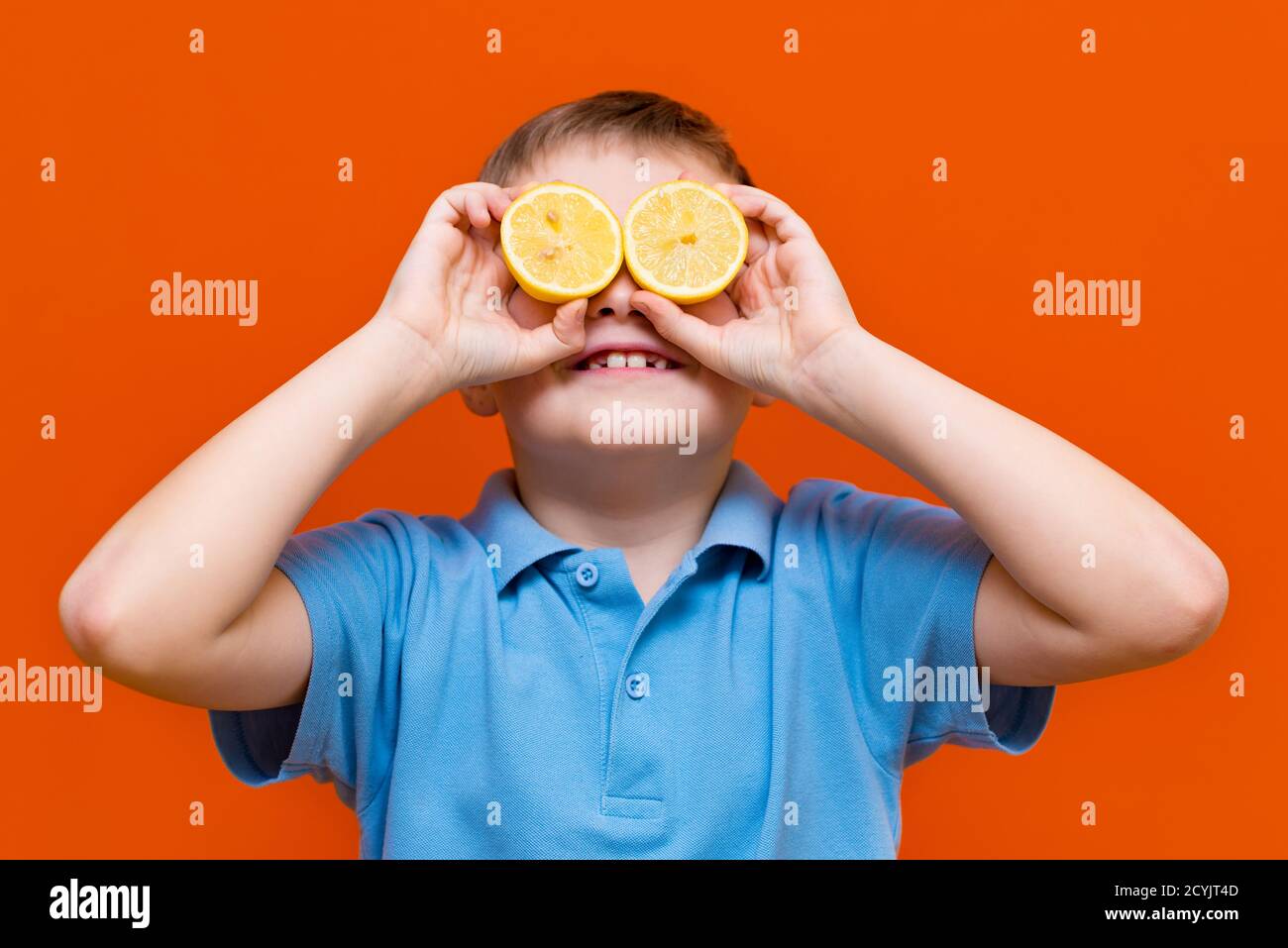 Close up Caucasian young child shows raw slices of lemon on a orange ...