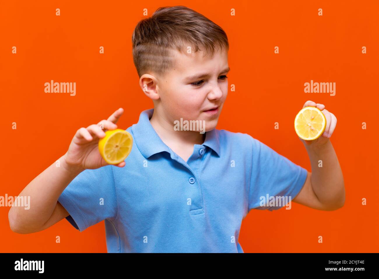 Close up Caucasian young child shows raw slices of lemon on a orange ...