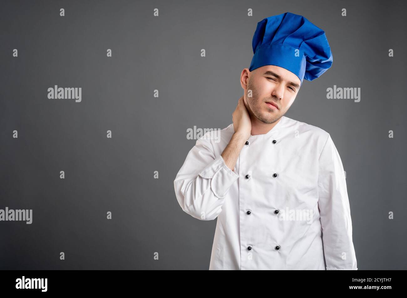 Portrait of young male dressed in a white chef suit with open arms ...