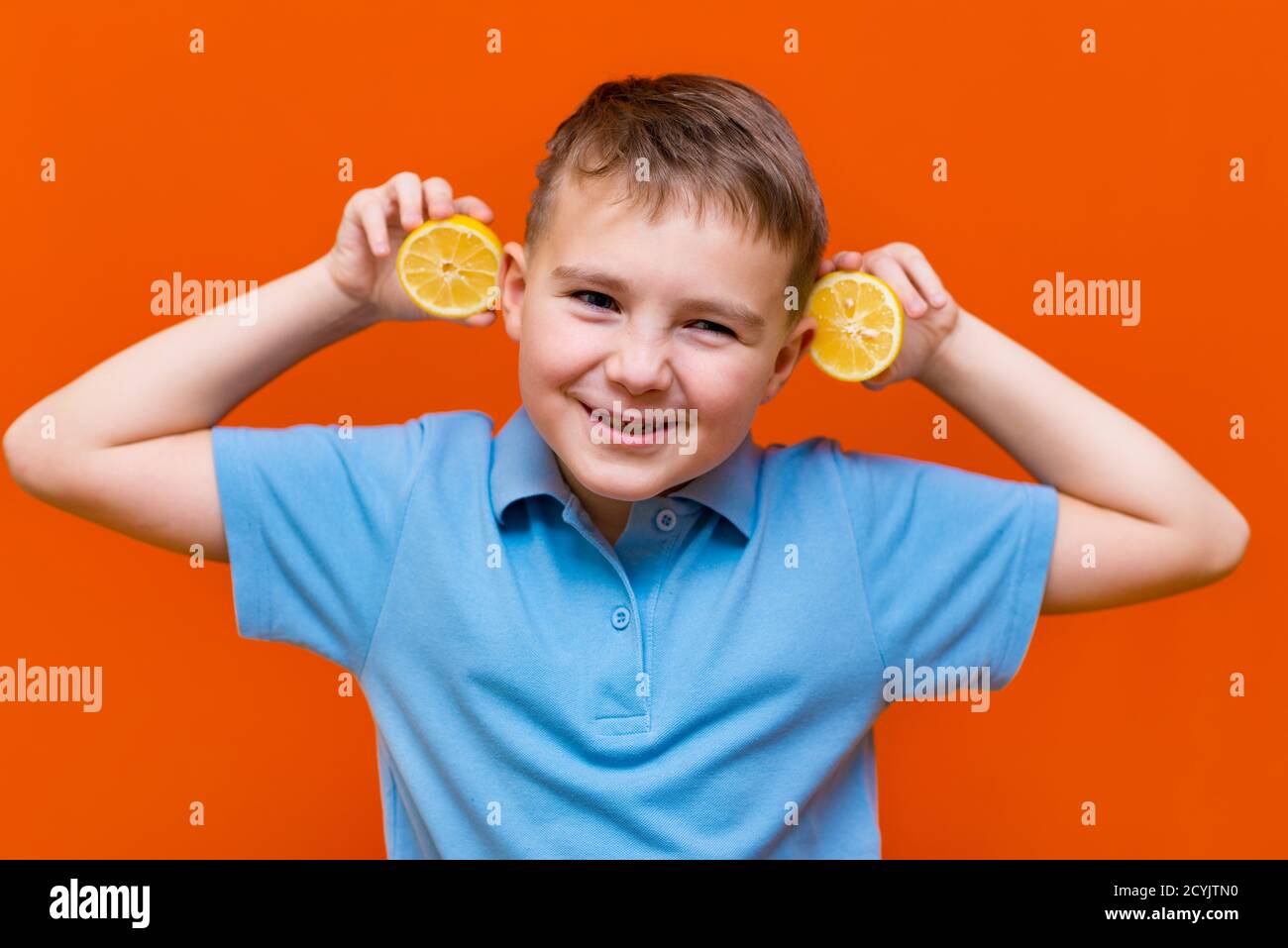 Close up Caucasian young child shows raw slices of lemon on a orange ...
