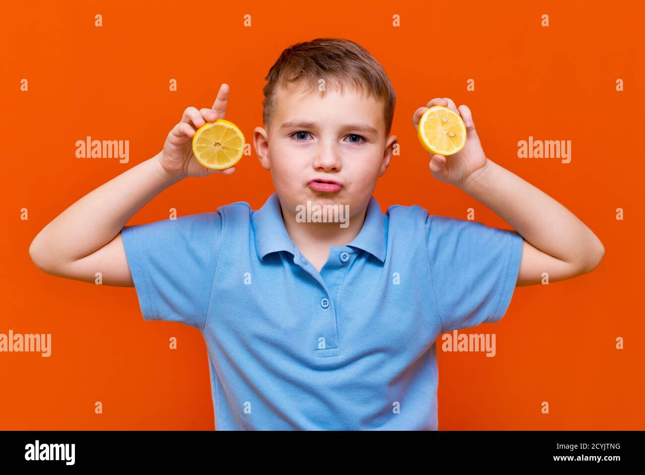 Close up Caucasian young child shows raw slices of lemon on a orange ...