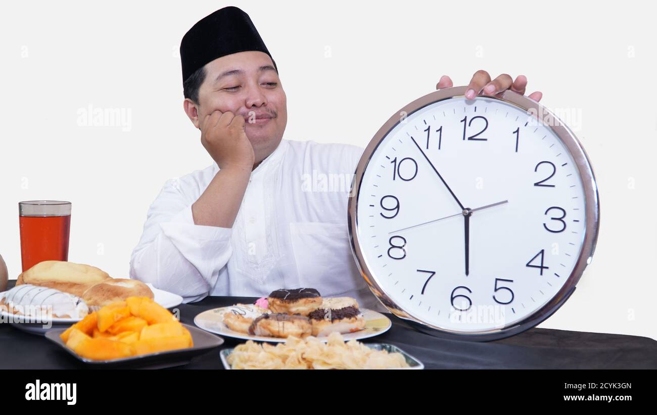 overweight man sitting and holding big round clock in front of sweet ...