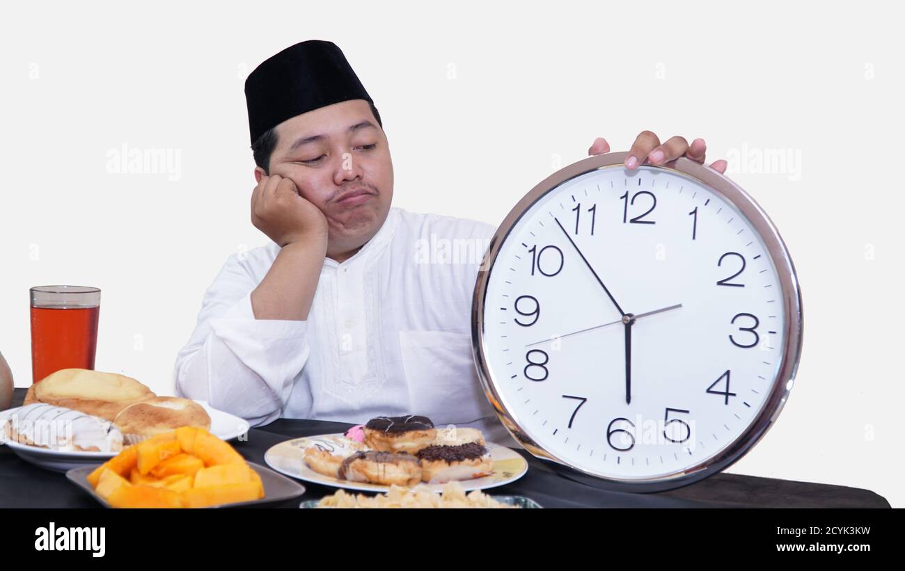 overweight man sitting and holding big round clock in front of sweet ...